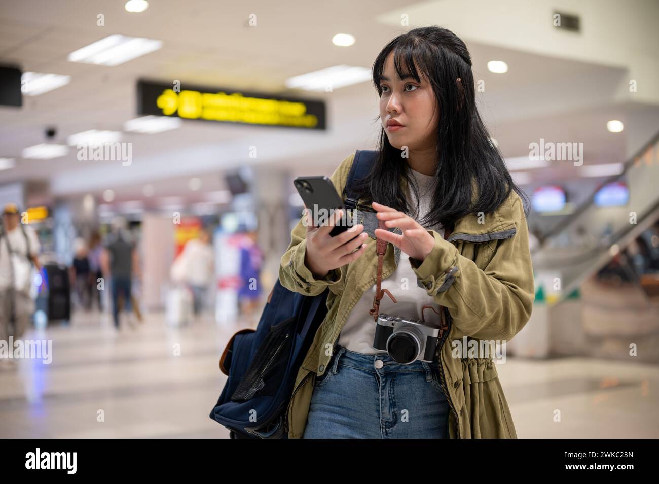 A serious young Asian female solo traveler or backpacker is walking in ...