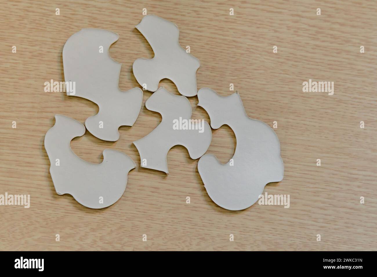 Assorted puzzle pieces laying upside down on brown wood grain tabletop ...