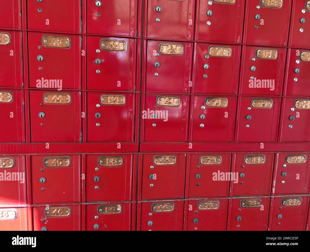 Rows of red metal vintage post office boxes on a wall in the post ...
