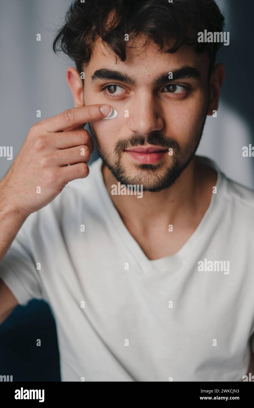 Front view portrait of a handsome man smearing face cream. Men's ...