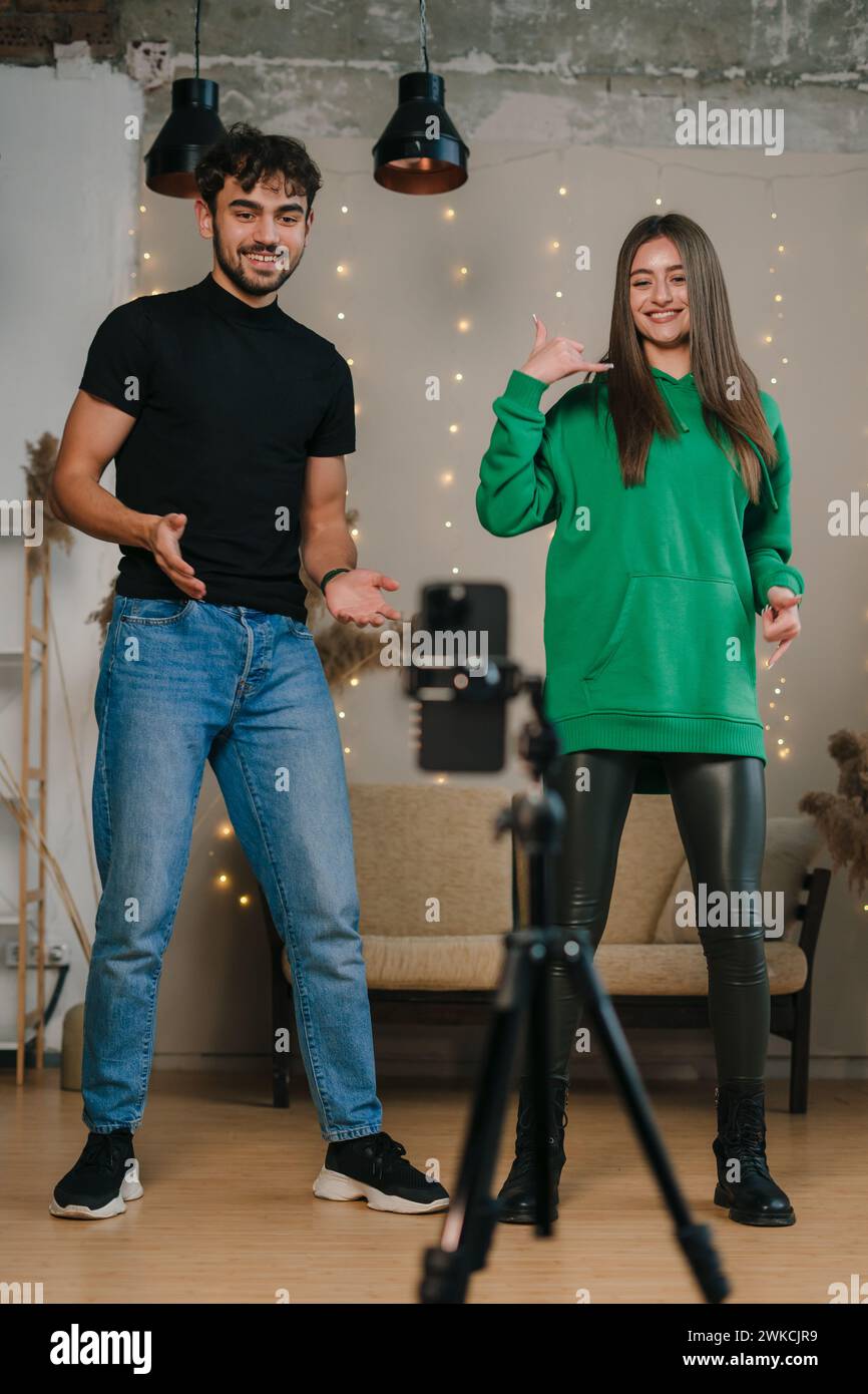 Vertical view of a cute couple making funny moves, dancing to popular ...