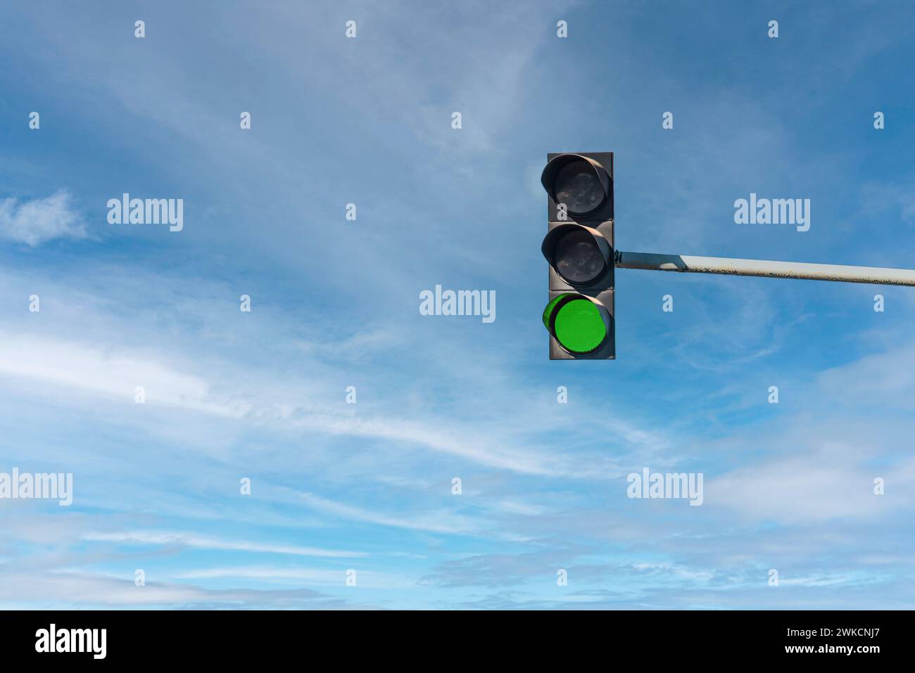 Modern traffic light with green light in front of cloudless sunny blue ...