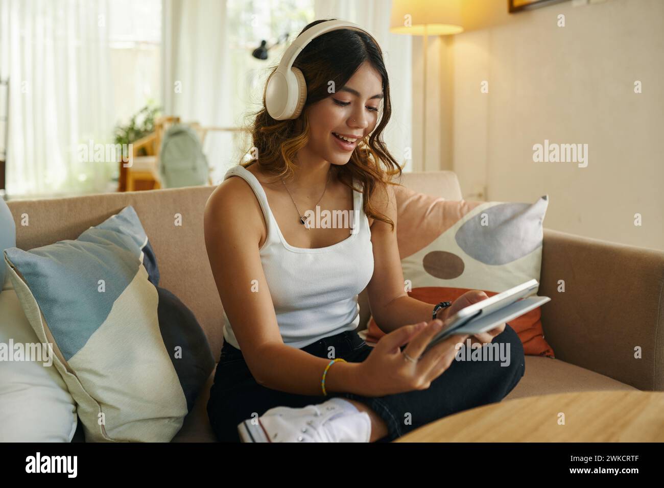 Smiling girl wearing headphones when video calling her friend Stock ...