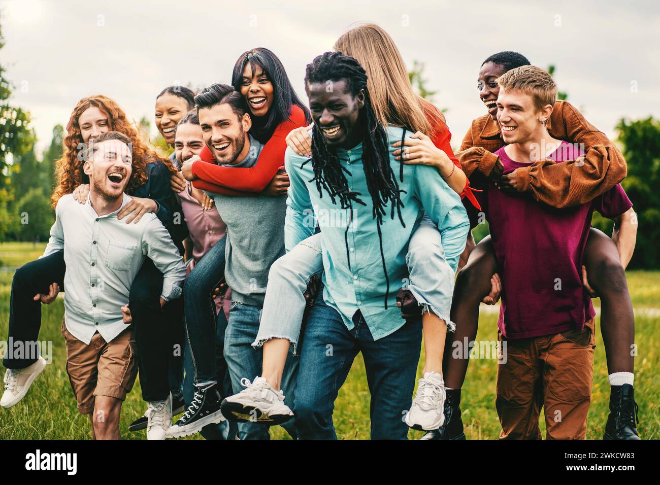 Diverse friends playing piggyback games outdoors - Joy and unity ...