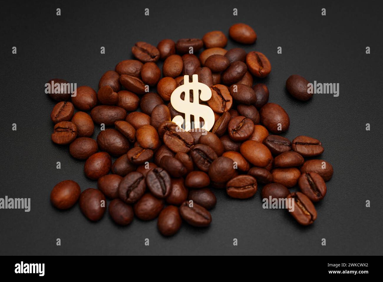 Golden dollar sign nestled within a pile of roasted coffee beans ...