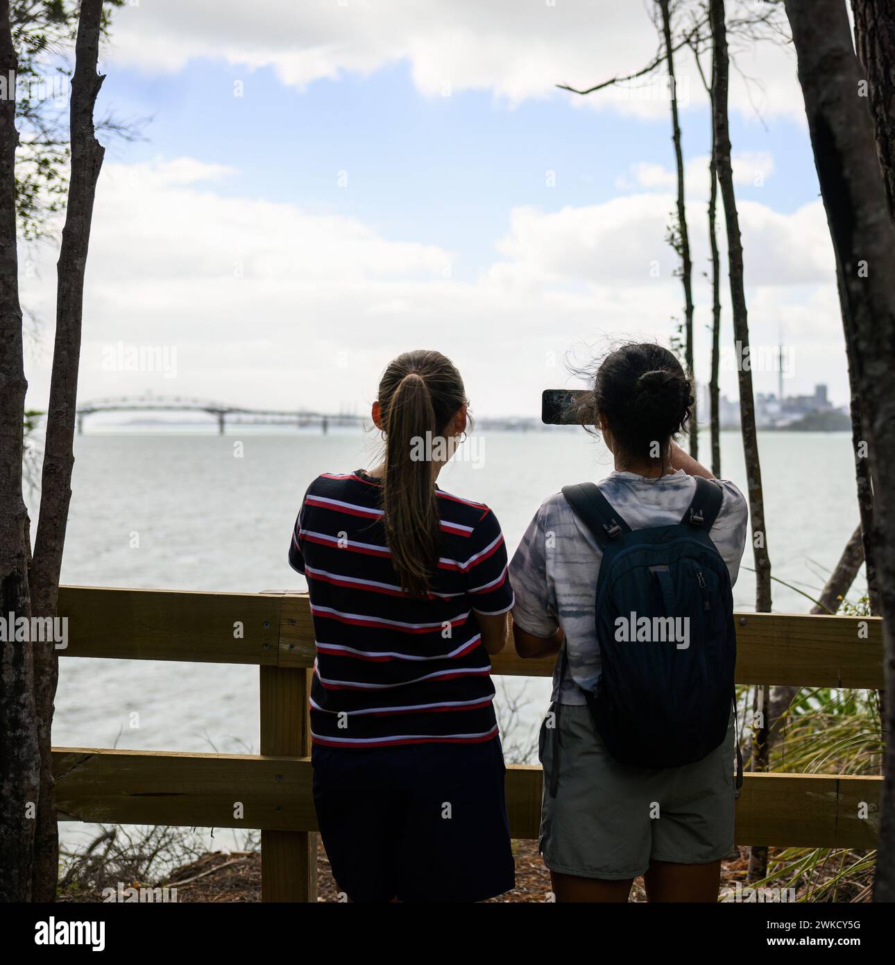 Woman taking photos of Auckland Harbour Bridge and Sky Tower using ...