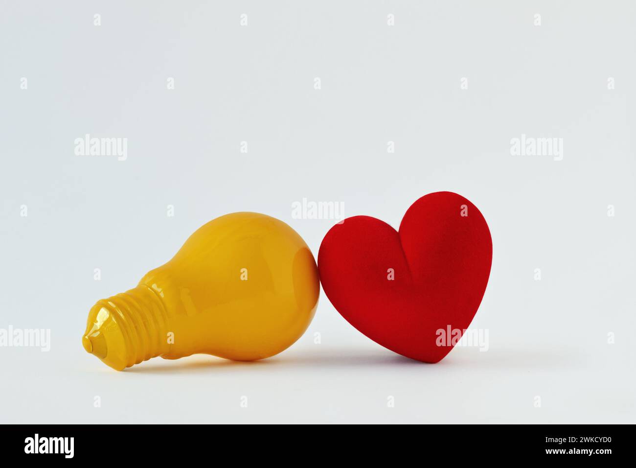 Yellow light bulb with heart on white background - Concept of heart and brain connection Stock ...