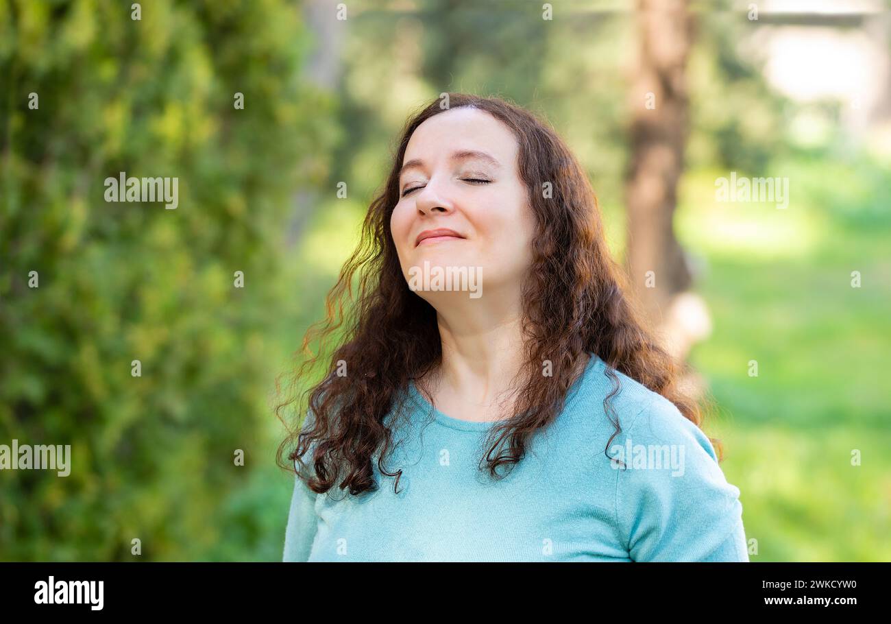 Woman breathing fresh air in a green forest in summer wearing a red ...
