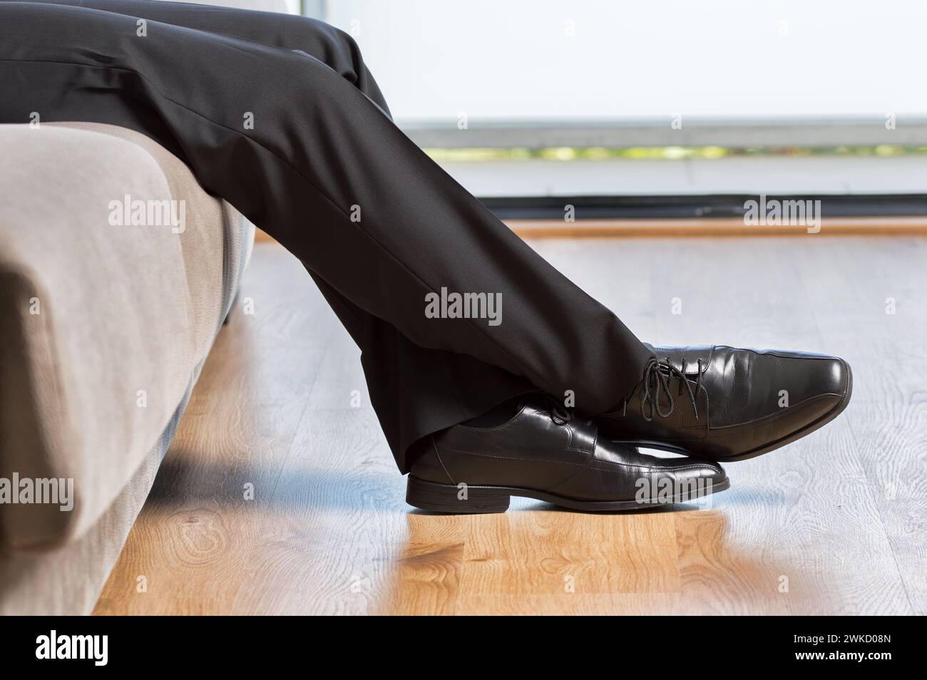 Profile of a tired businessman legs with suit sitting on couch at home ...