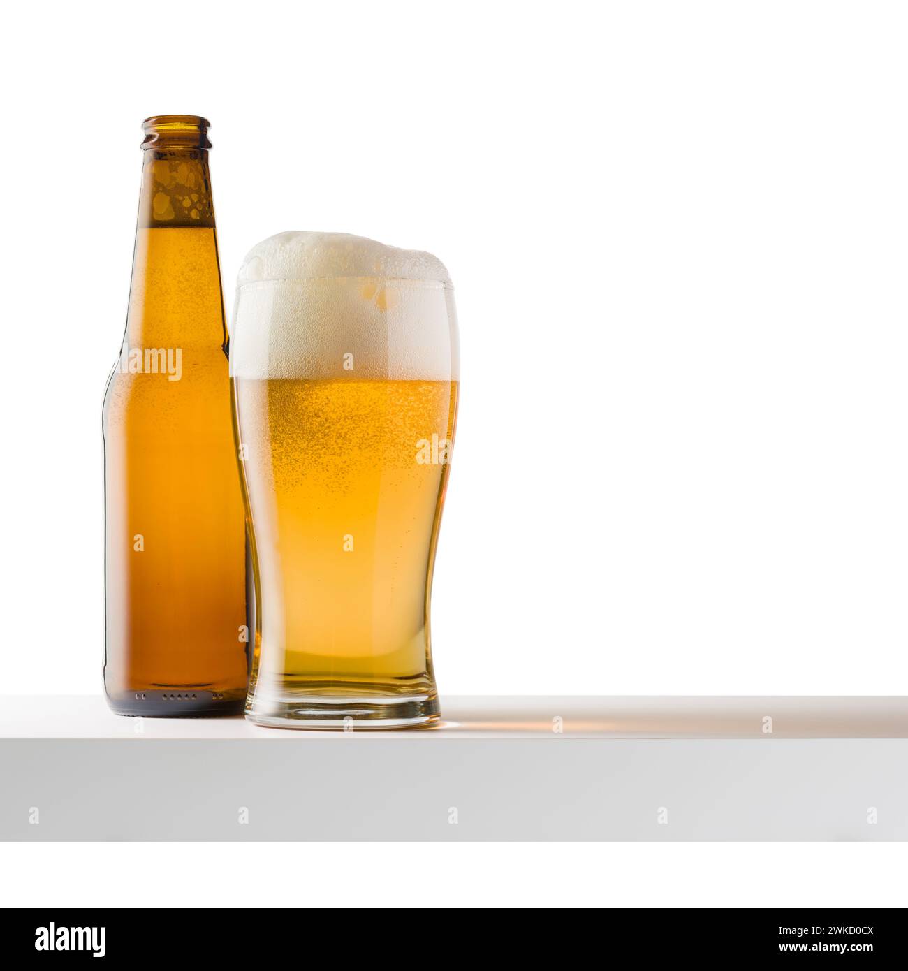 Glass of blonde beer with bottle on white shelf, isolated on white ...