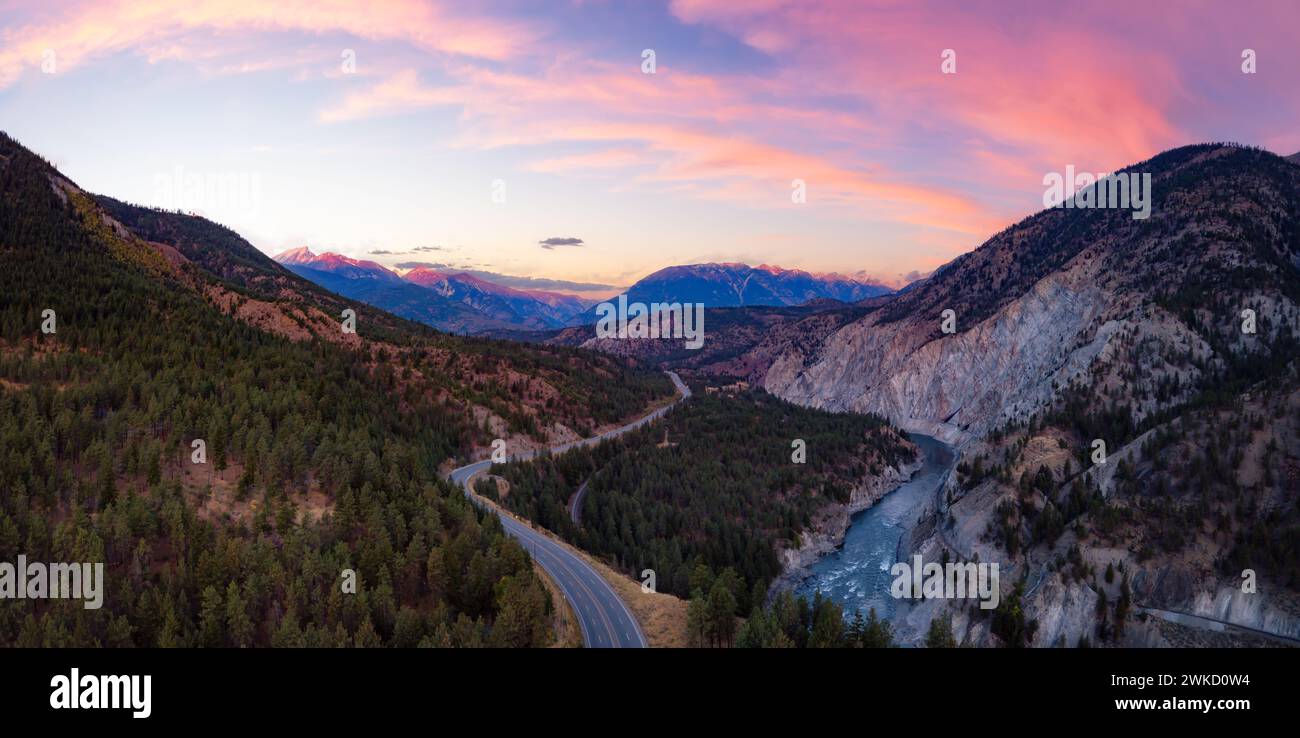 An aerial view of a winding road in a mountain valley at sunrise near ...