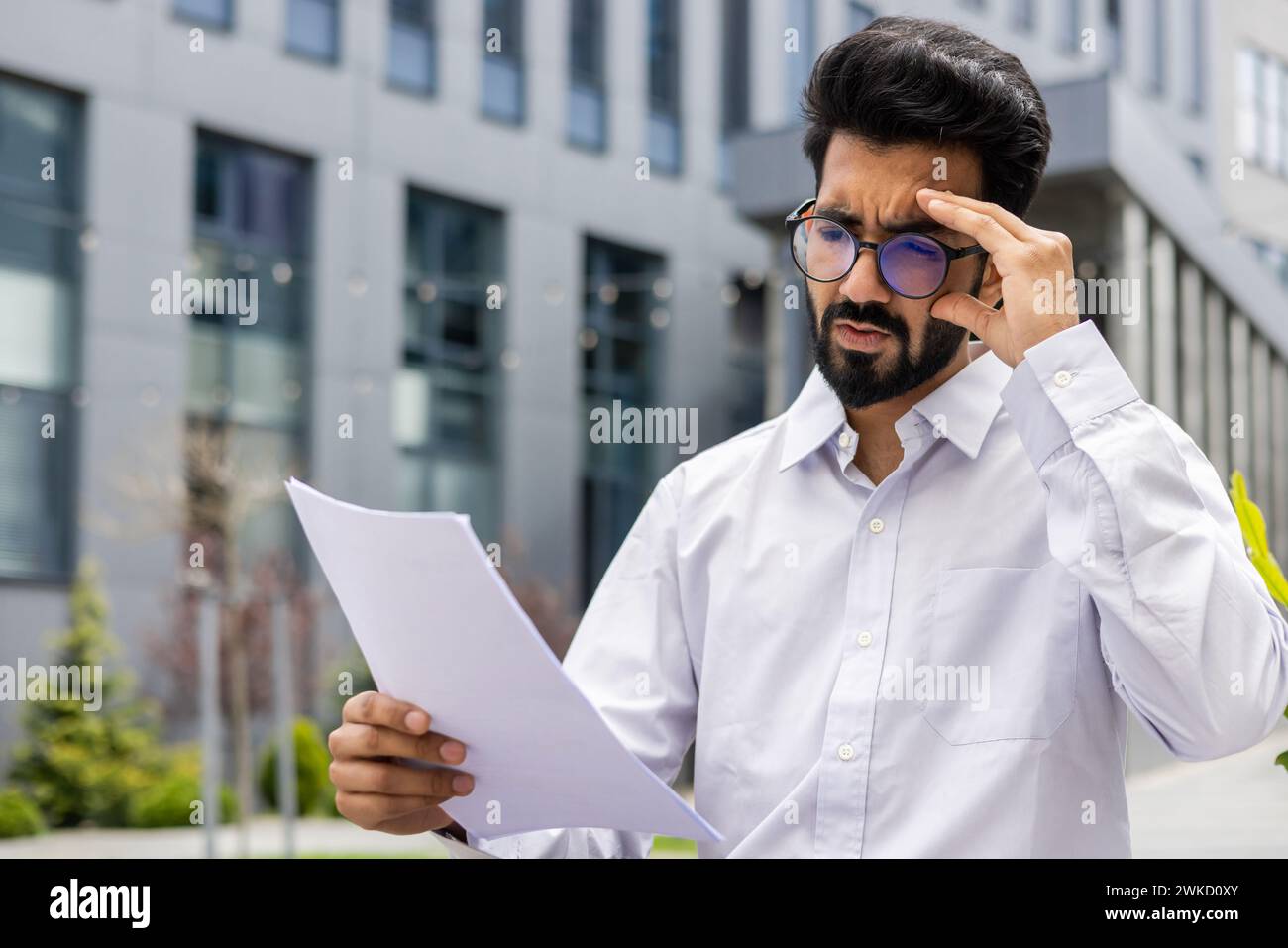 Focused entrepreneur reading paperwork with a concerned expression ...
