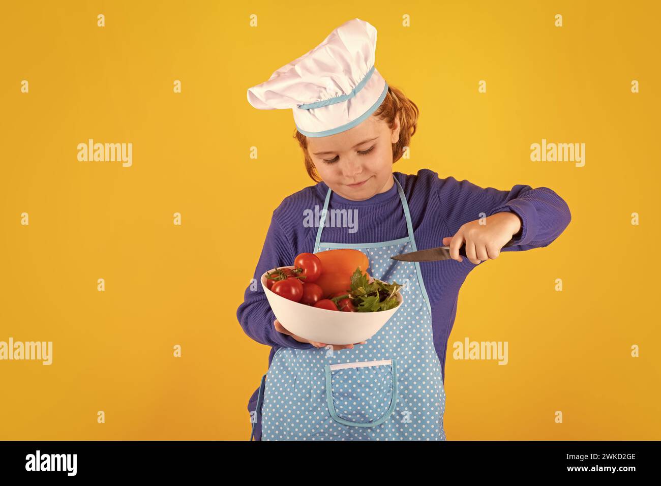 Kid cook hold plate with vegetables. Child chef cook prepares food on ...