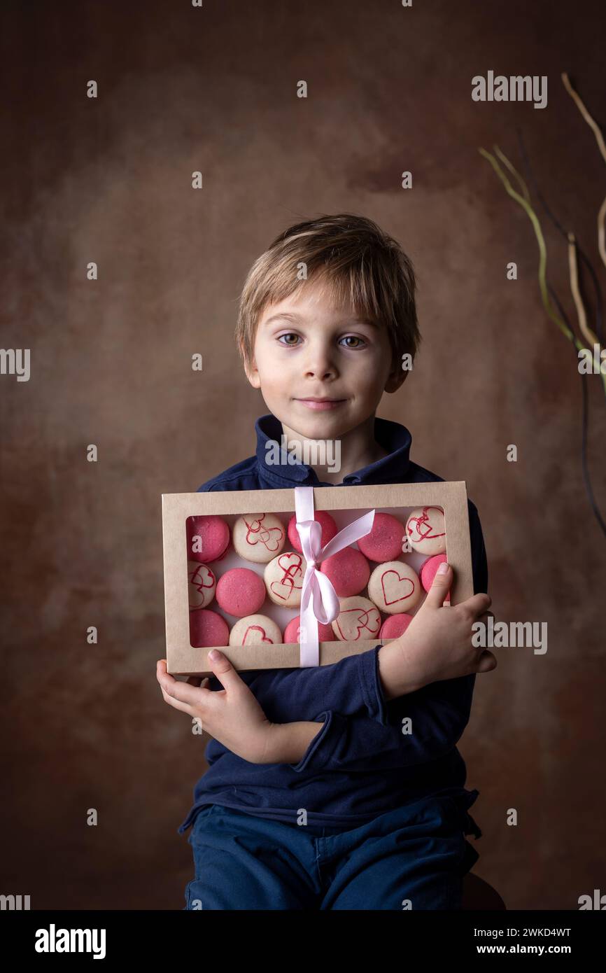 Beautiful blond child, boy, holding box with sweet macaroons for ...