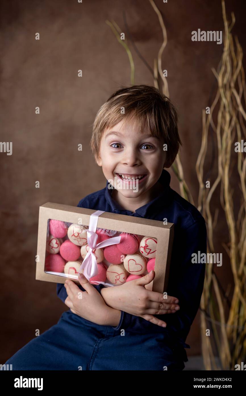 Beautiful blond child, boy, holding box with sweet macaroons for ...