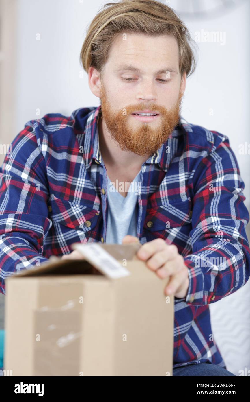handsome young man opening box with parcel Stock Photo - Alamy