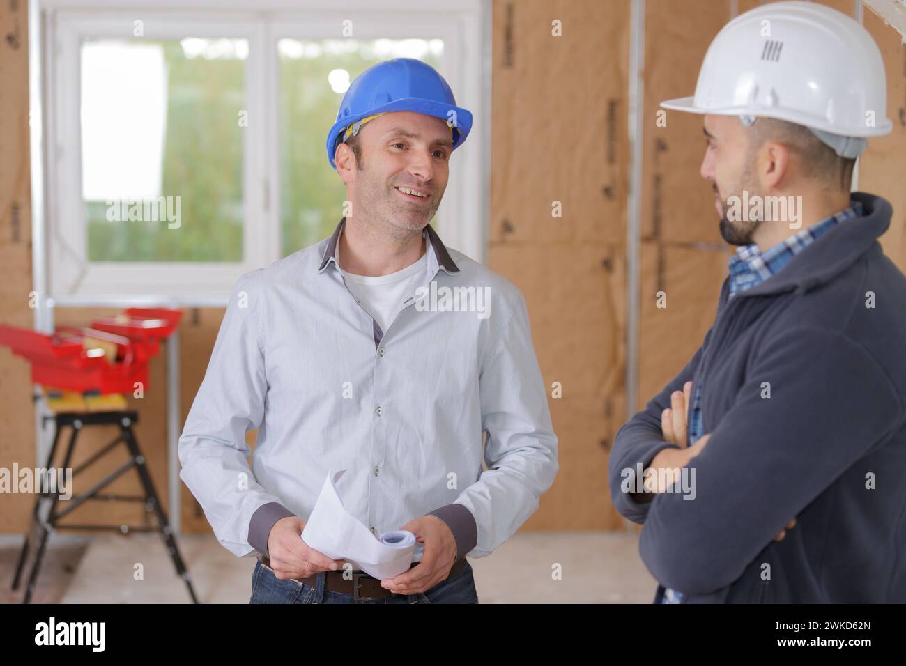 senior architect and young builder discussing the unfinished project ...