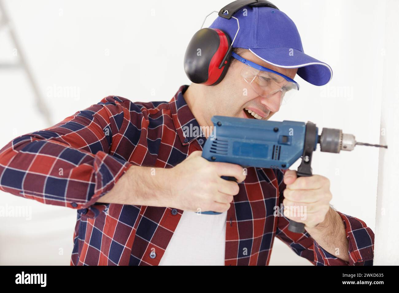 man struggling to pierce hole with electric drill Stock Photo - Alamy