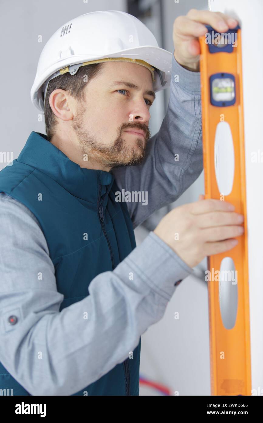 handyman measuring angle of wall with level Stock Photo - Alamy
