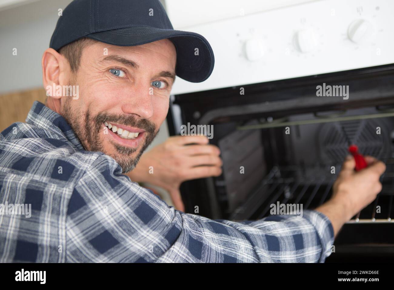 happy man fitting new cooker in kitchen Stock Photo - Alamy