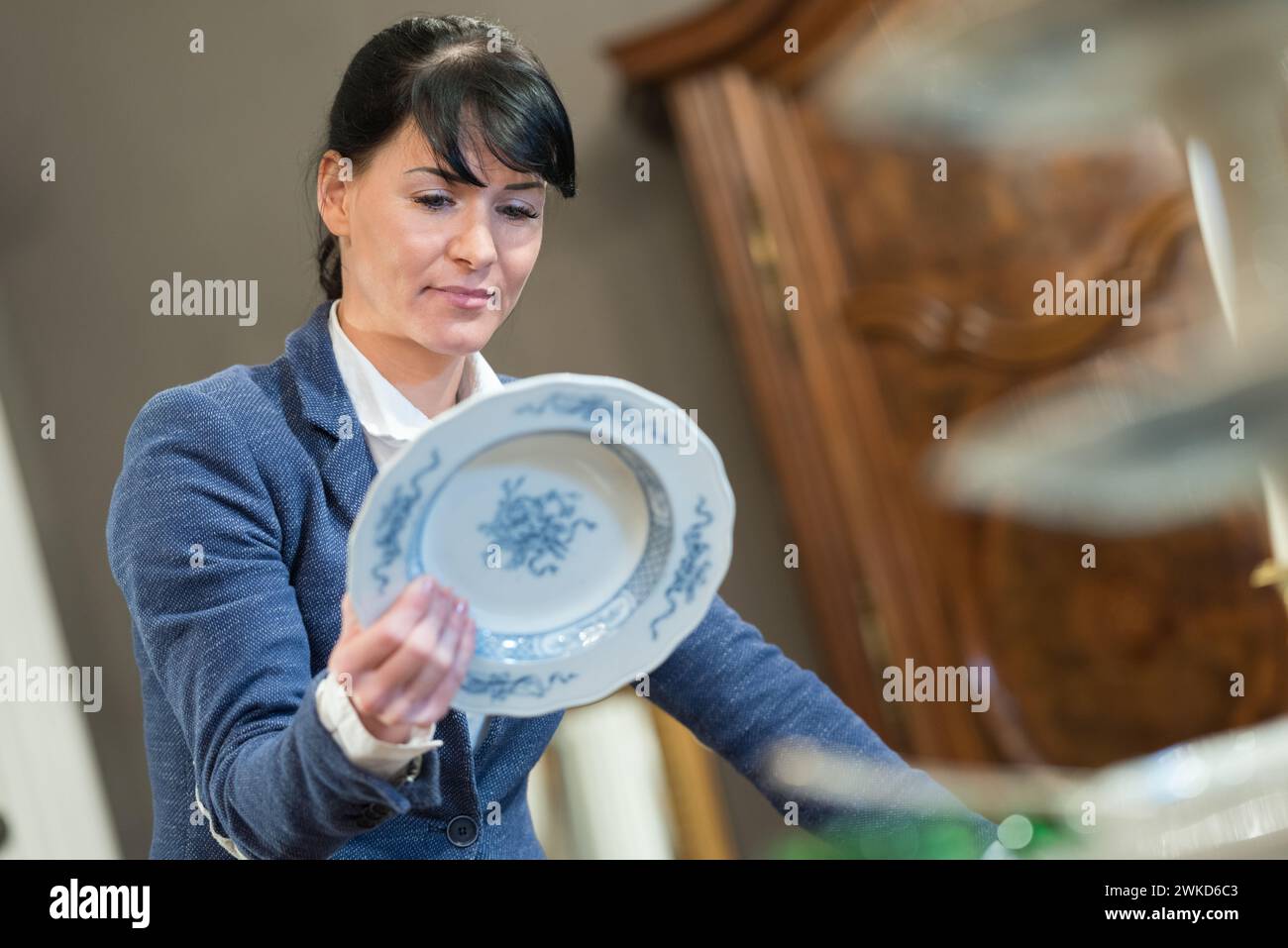woman inspecting underside of antique plate to identify it Stock Photo ...