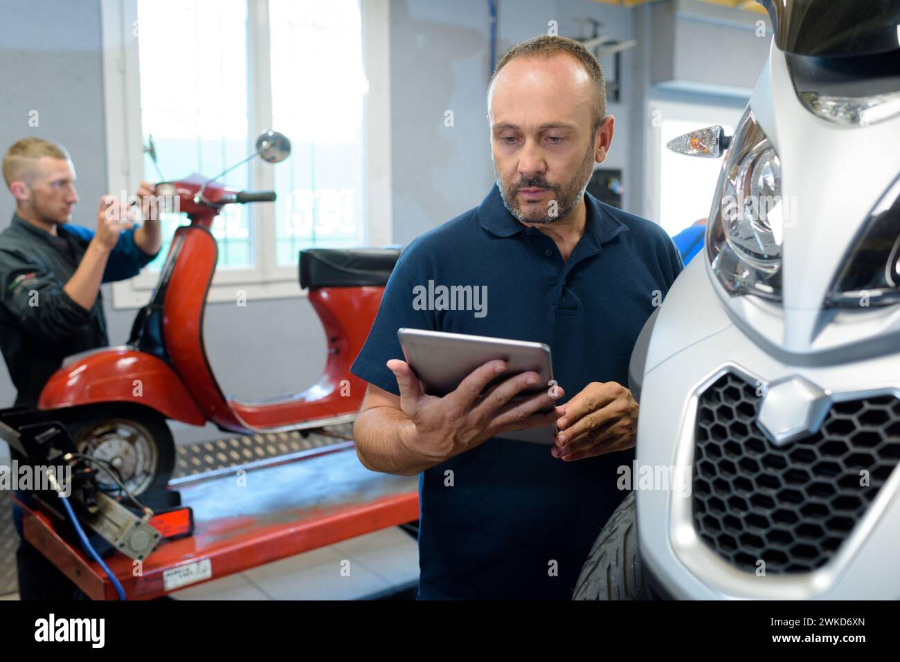 scooter senior mechanic checking details Stock Photo - Alamy