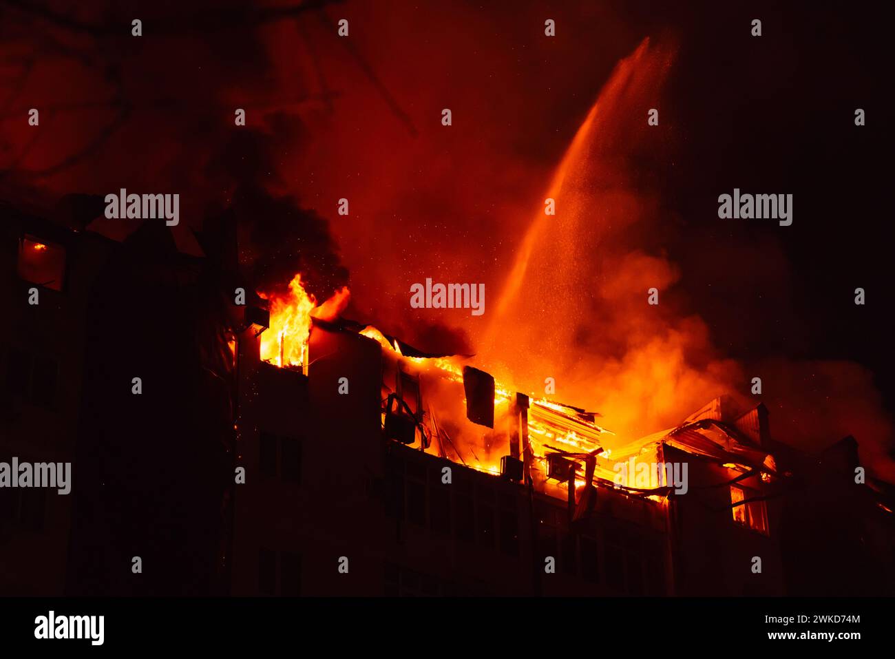 Burning house is engulfed in flames at night. Firefighters extinguish ...