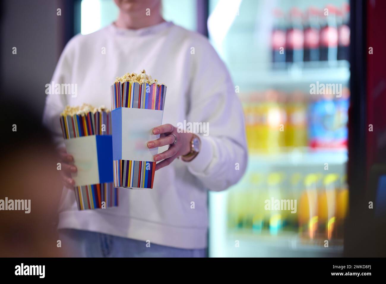 A vendor stands outside the cinema, holding freshly popped popcorn to ...
