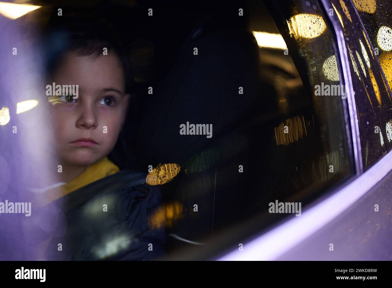 A young boy enjoys a car ride, captured through the window, as he ...