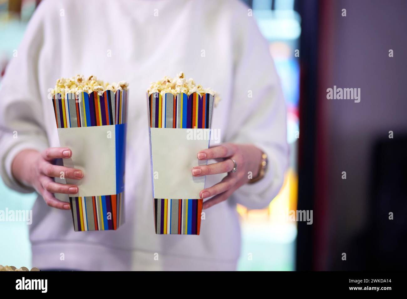 A vendor stands outside the cinema, holding freshly popped popcorn to ...