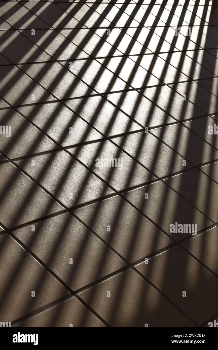 The sunlight illuminating tiled floor creating grid shadows Stock Photo ...