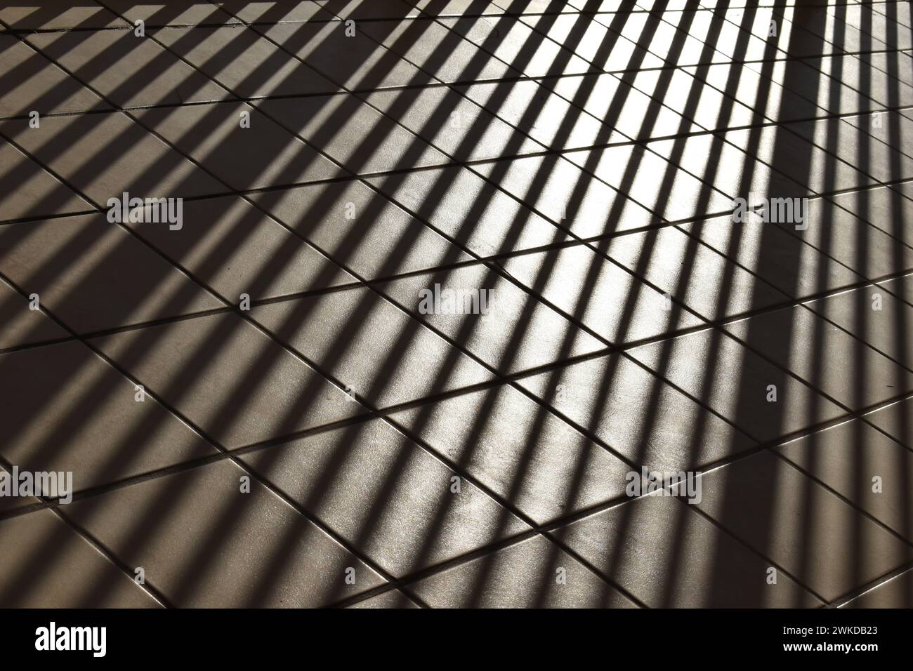 The sunlight illuminating tiled floor creating grid shadows Stock Photo ...