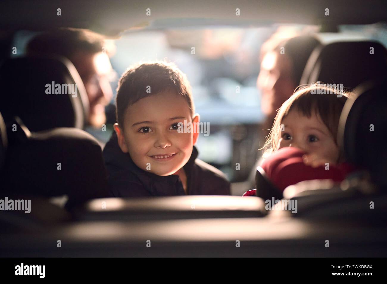 A young brother and sister enjoying a car ride together, immersed in ...
