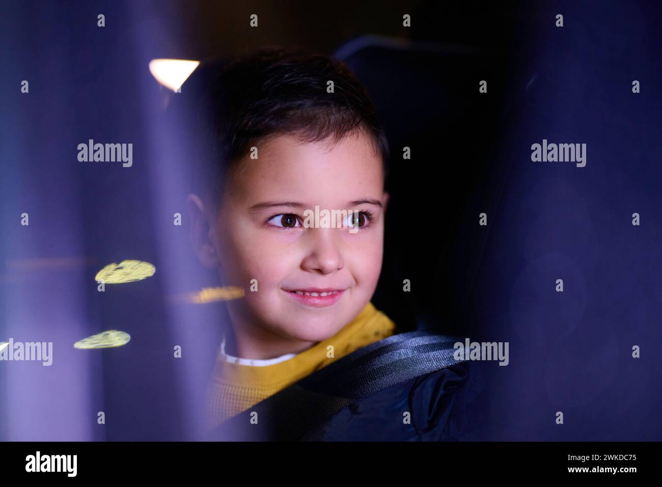 A young boy enjoys a car ride, captured through the window, as he ...