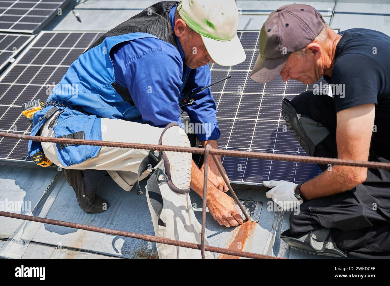 Workers building solar panel system on metal rooftop of house. Two men ...