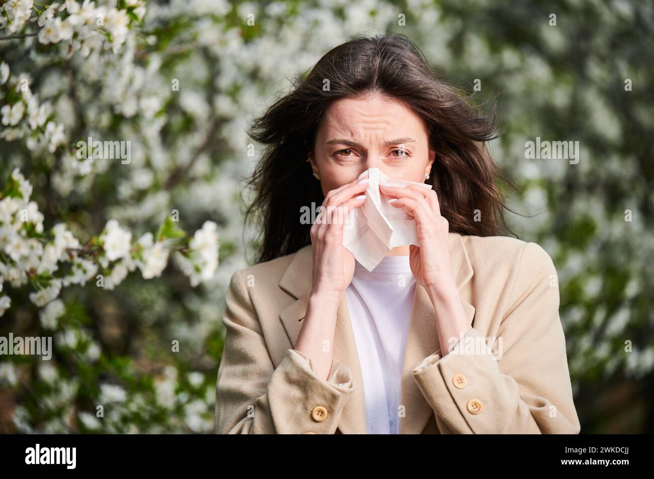 Woman allergic suffering from seasonal allergy at spring in blossoming ...
