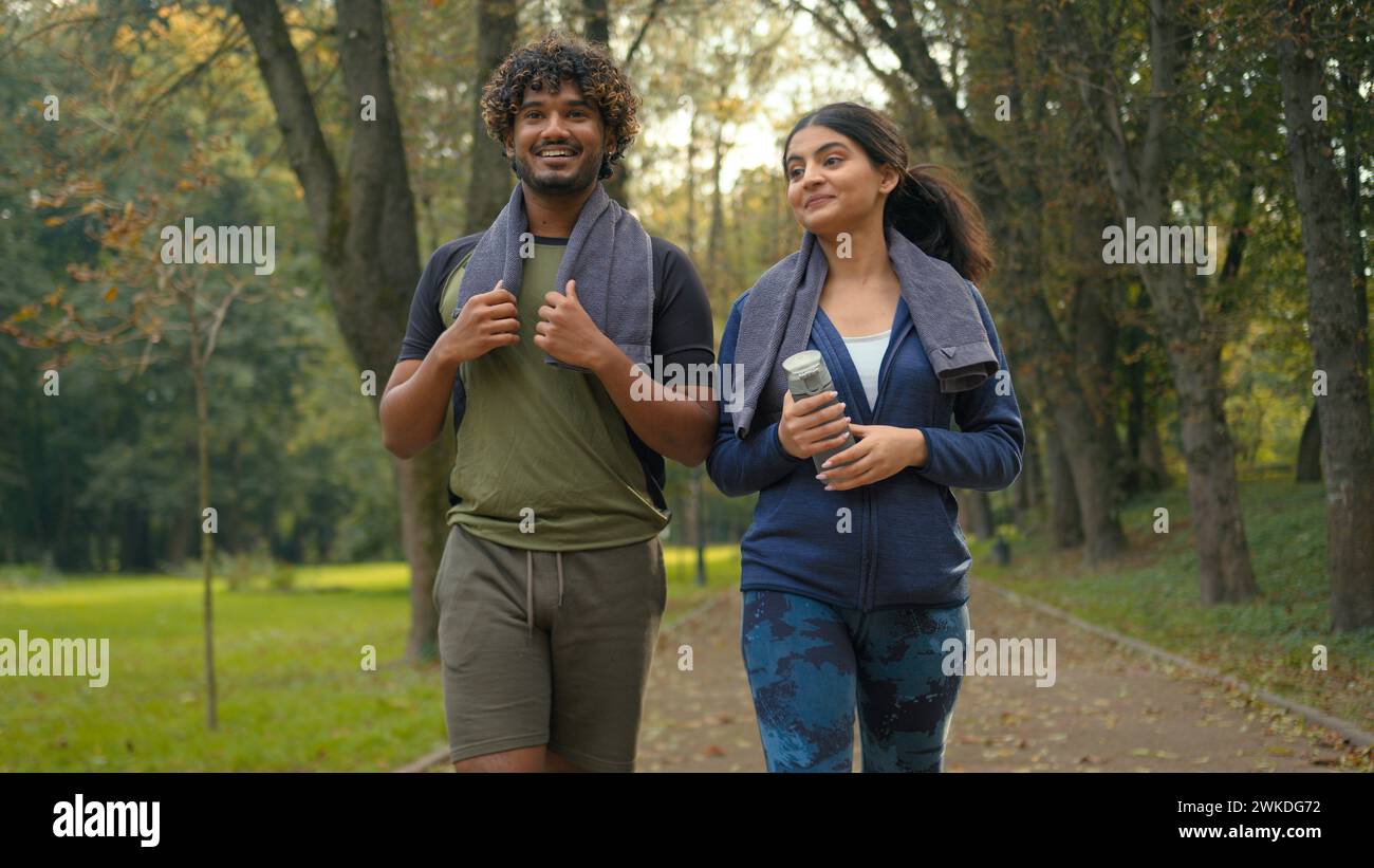 Outdoors in nature park Indian Arabian couple friends man woman walking ...