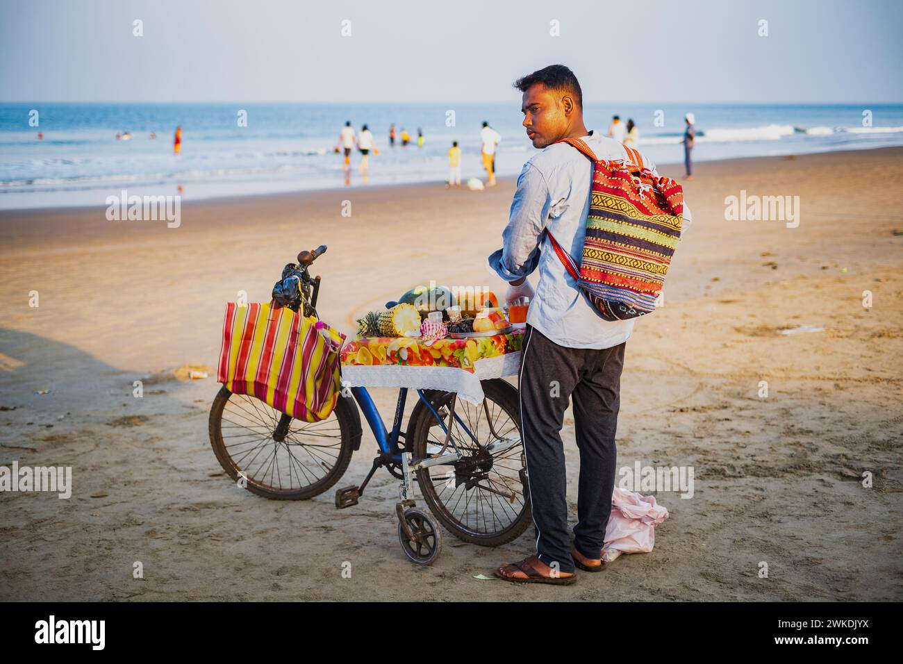 Man selling fruits and coconuts on a bicycle along the seashore in Goa ...