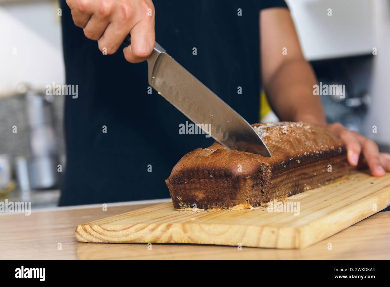 close-up of male hands in kitchen at home cutting sponge cake on ...