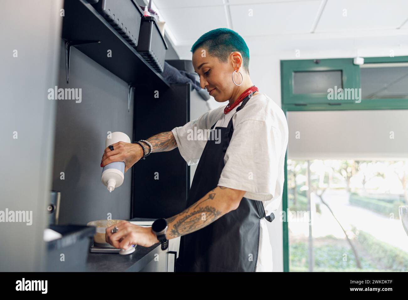 Female colorist preparing a hair dye in a container while working in ...