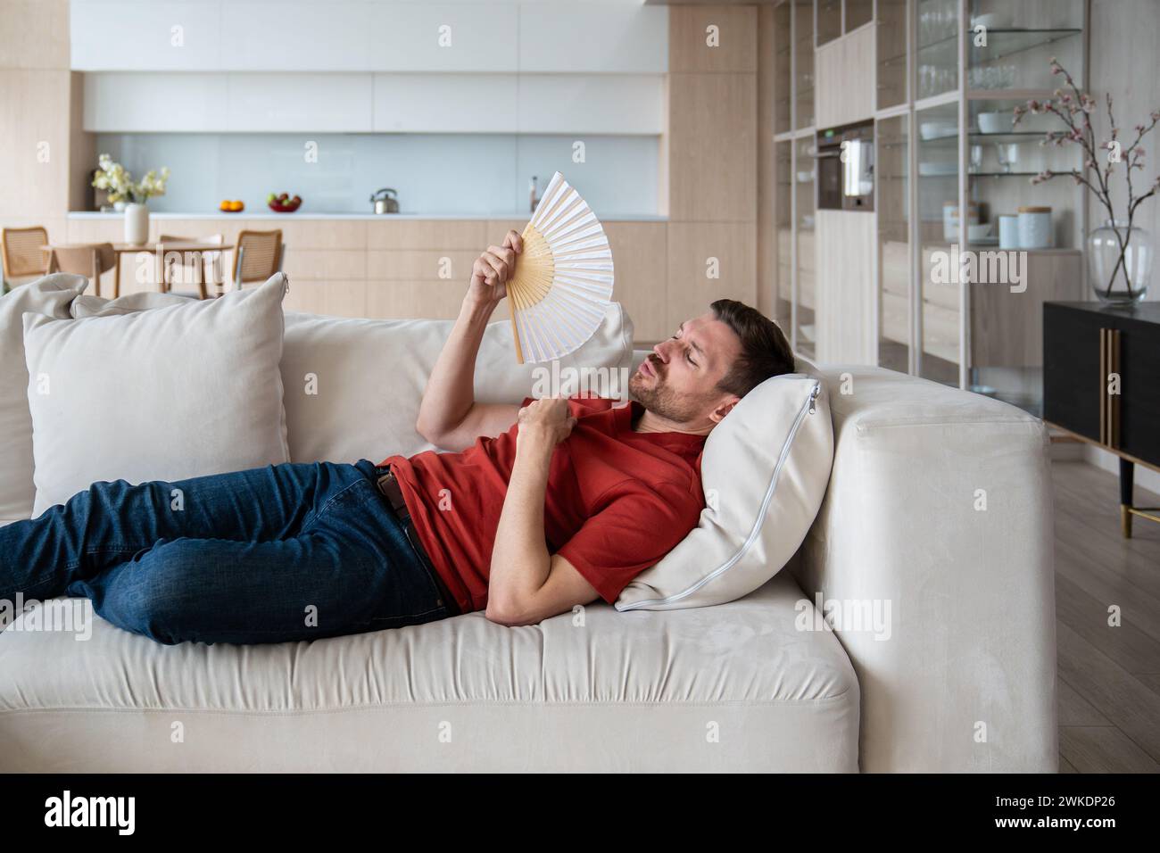 Exhausted overheated man waving with hand paper fan, suffering from ...