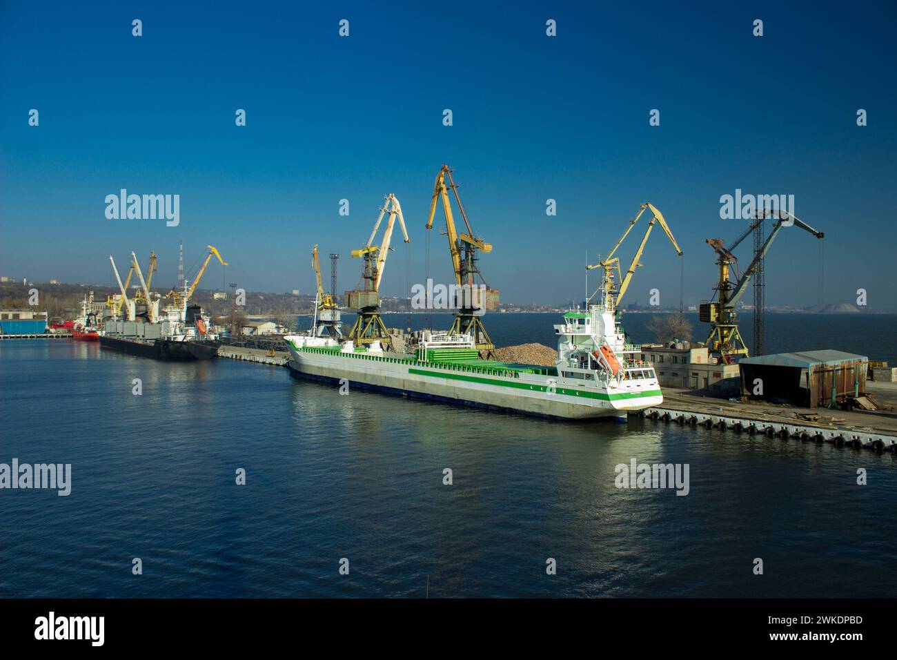 Cargo ship docking at seaport for transshipment. Cranes load containers for international trade ...