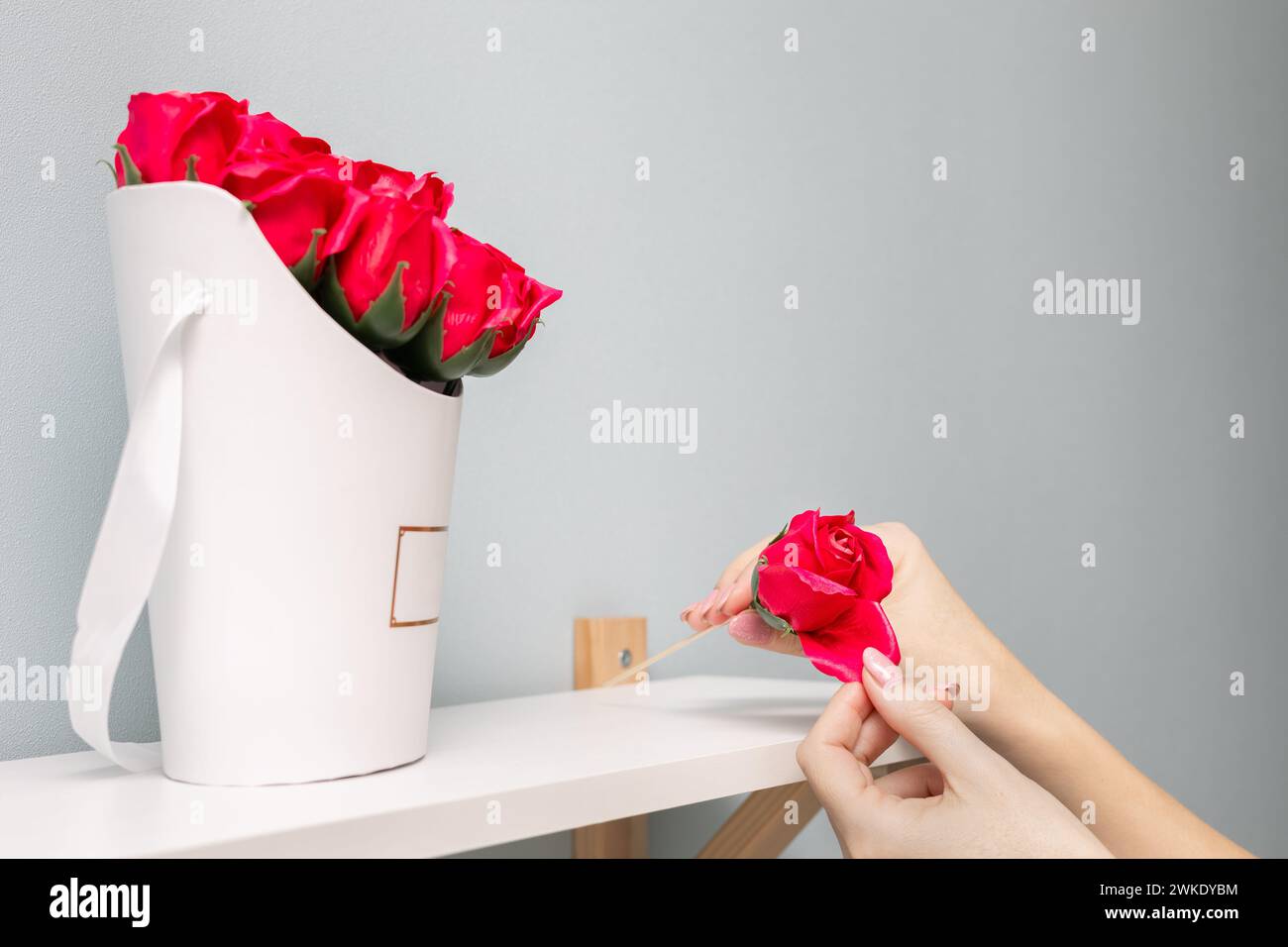 a woman's hand tears a petal from a rose. bouquet of artificial roses ...