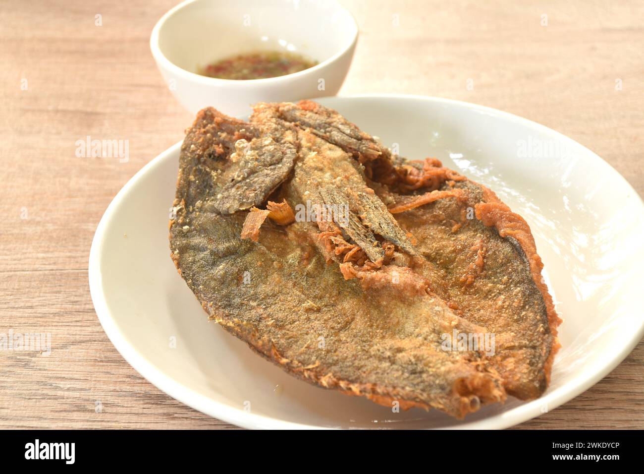 deep fried black-banded trevally fish on plate dipping spicy chili ...