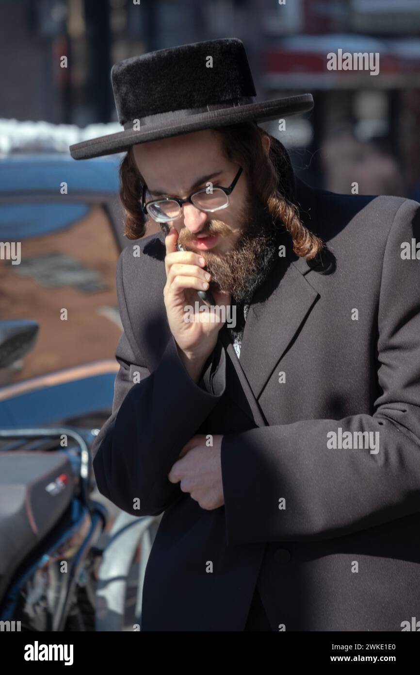 A head & shoulders portrait of a hasidic Jewish man talking on his flip ...