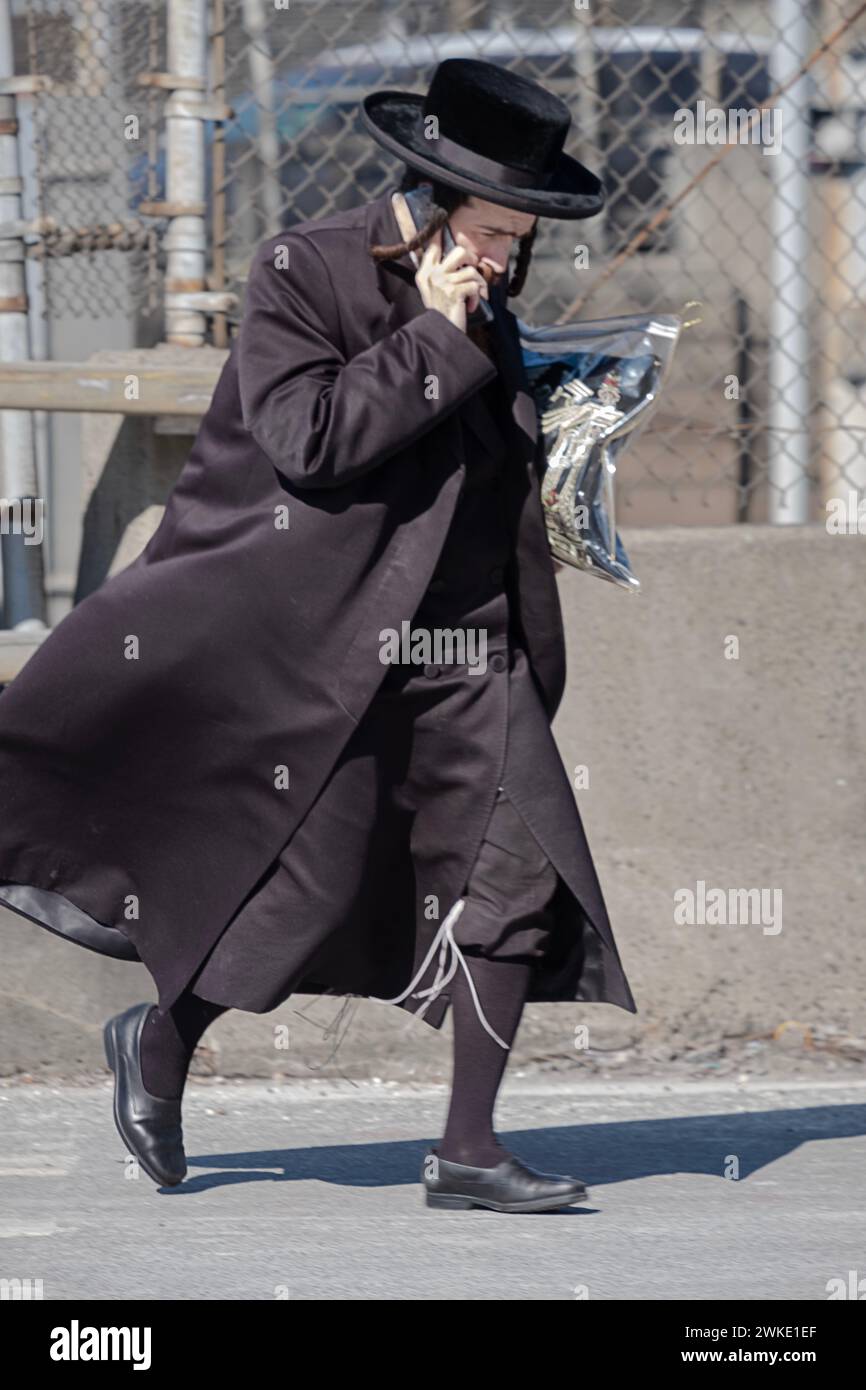 An orthodox Jewish man talks on his flip phone while heading home from ...