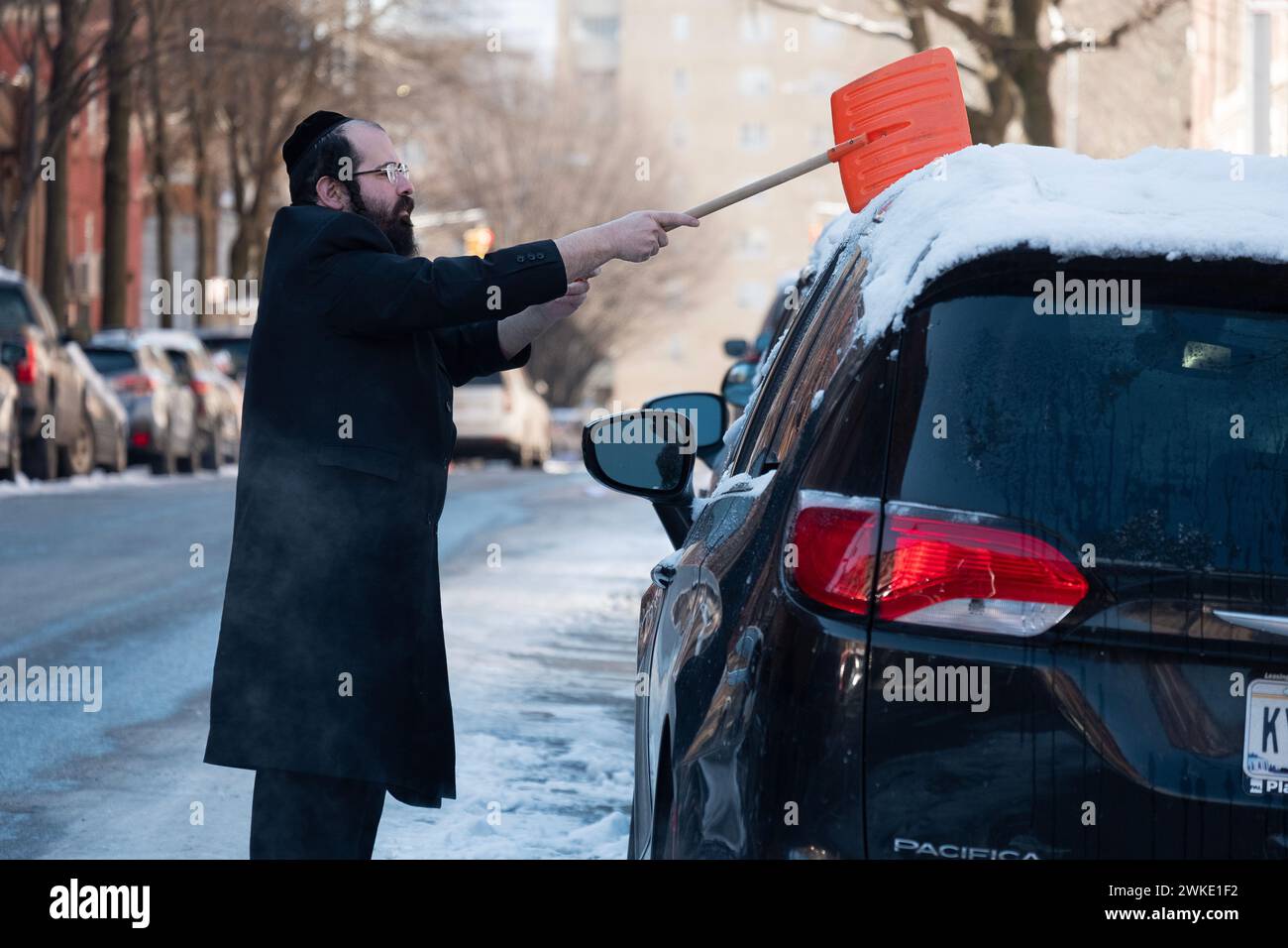On a cold winter morning an orthodox Jewish man cleans the snow off his ...