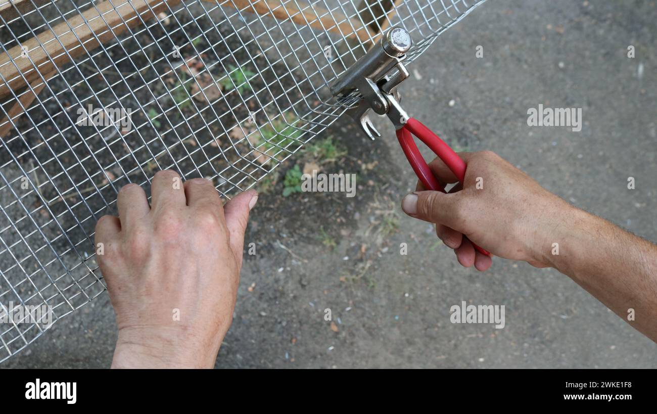 pinching the edge of a mesh grid with tongs during the production of a ...