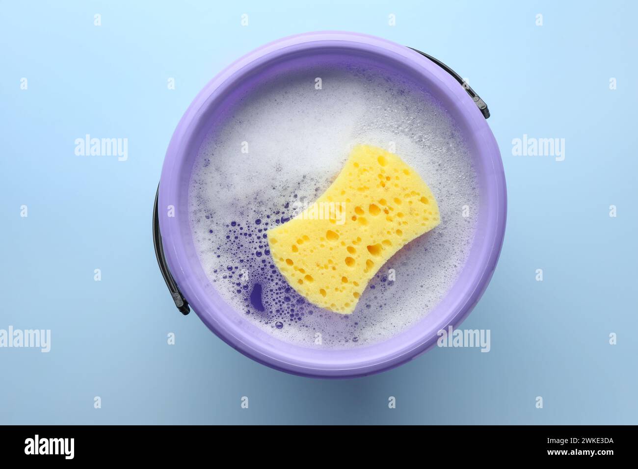Bucket with foam and sponge on light blue background, top view Stock ...