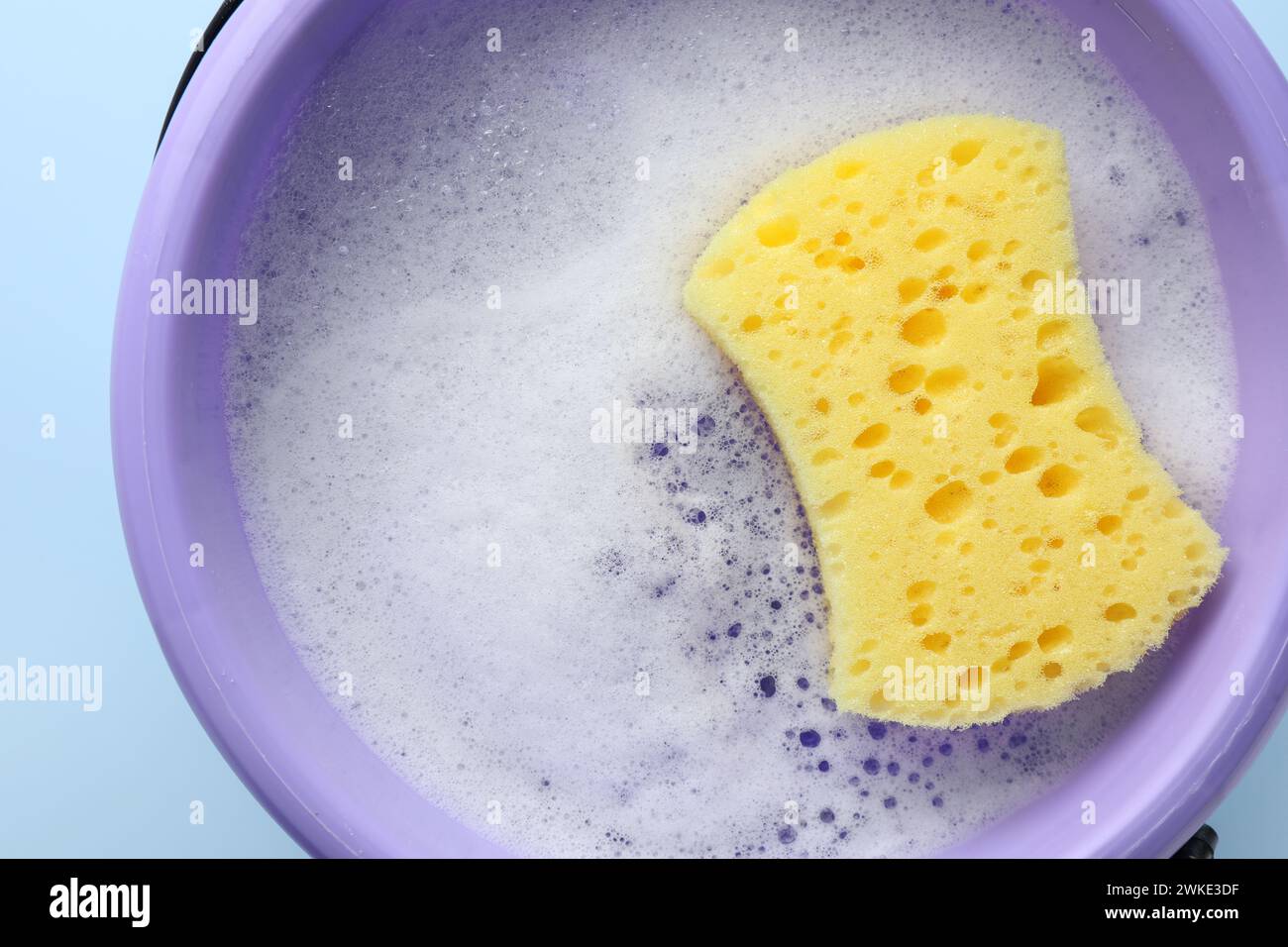 Bucket with foam and sponge on light blue background, top view Stock ...